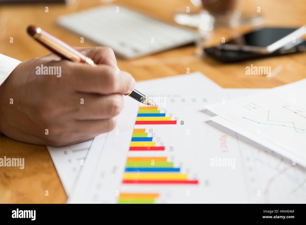businessman hand holding pen with graph and chart analysis paperwork ...