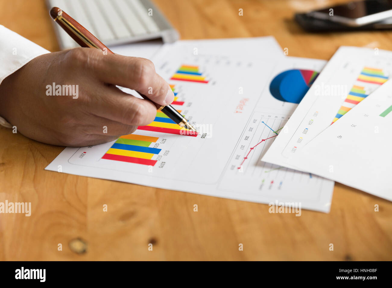 businessman hand holding pen with graph and chart analysis paperwork ...