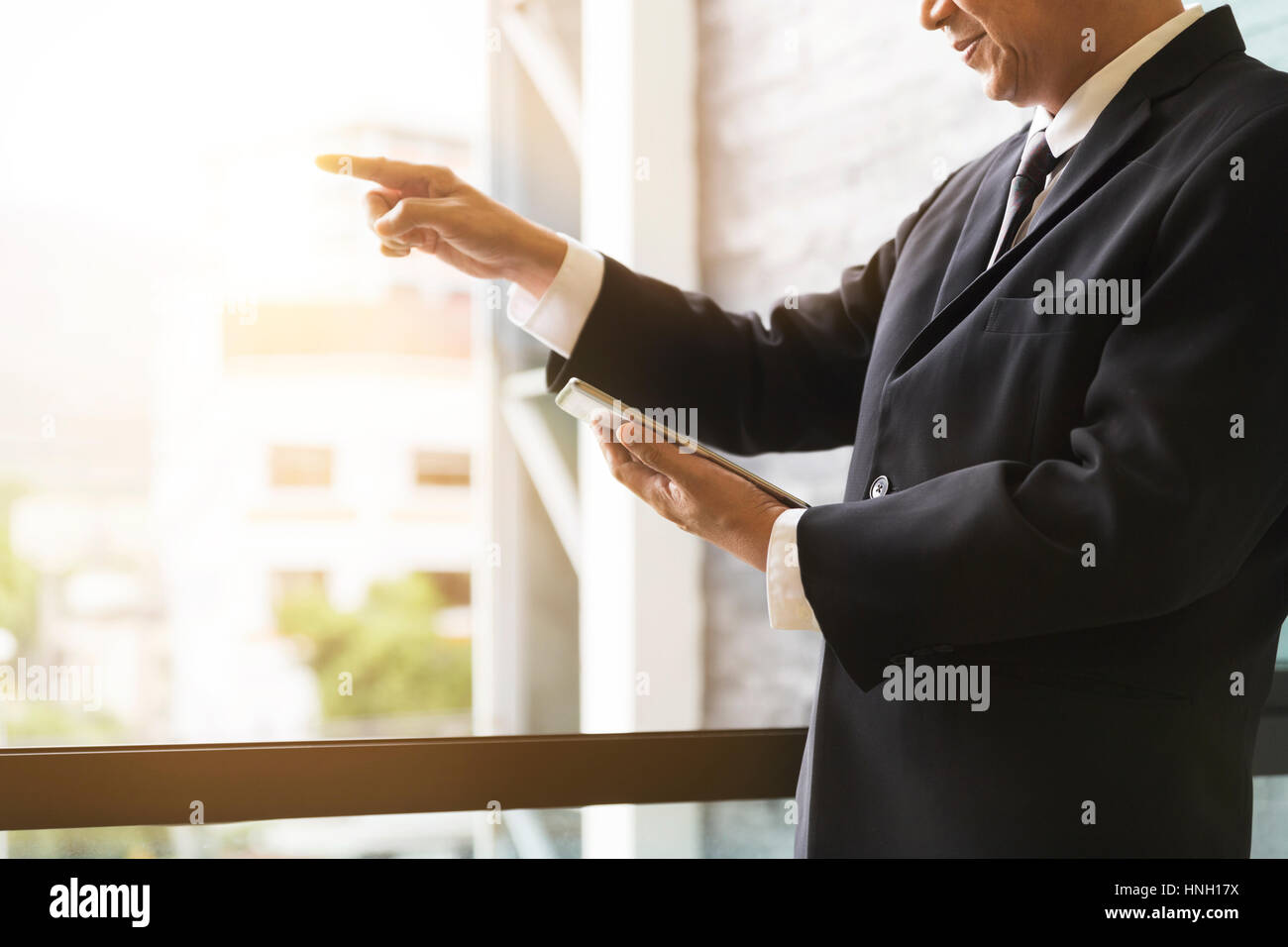 businessman holding tablet and pointing his finger out of window Stock ...