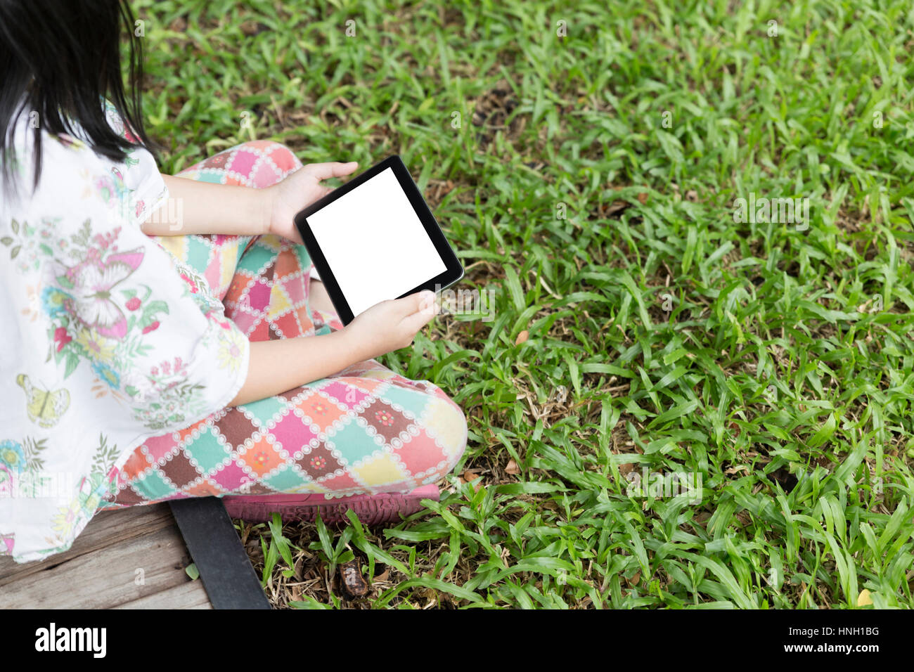 girl holding digital tablet sitting on grass lawn yard Stock Photo - Alamy