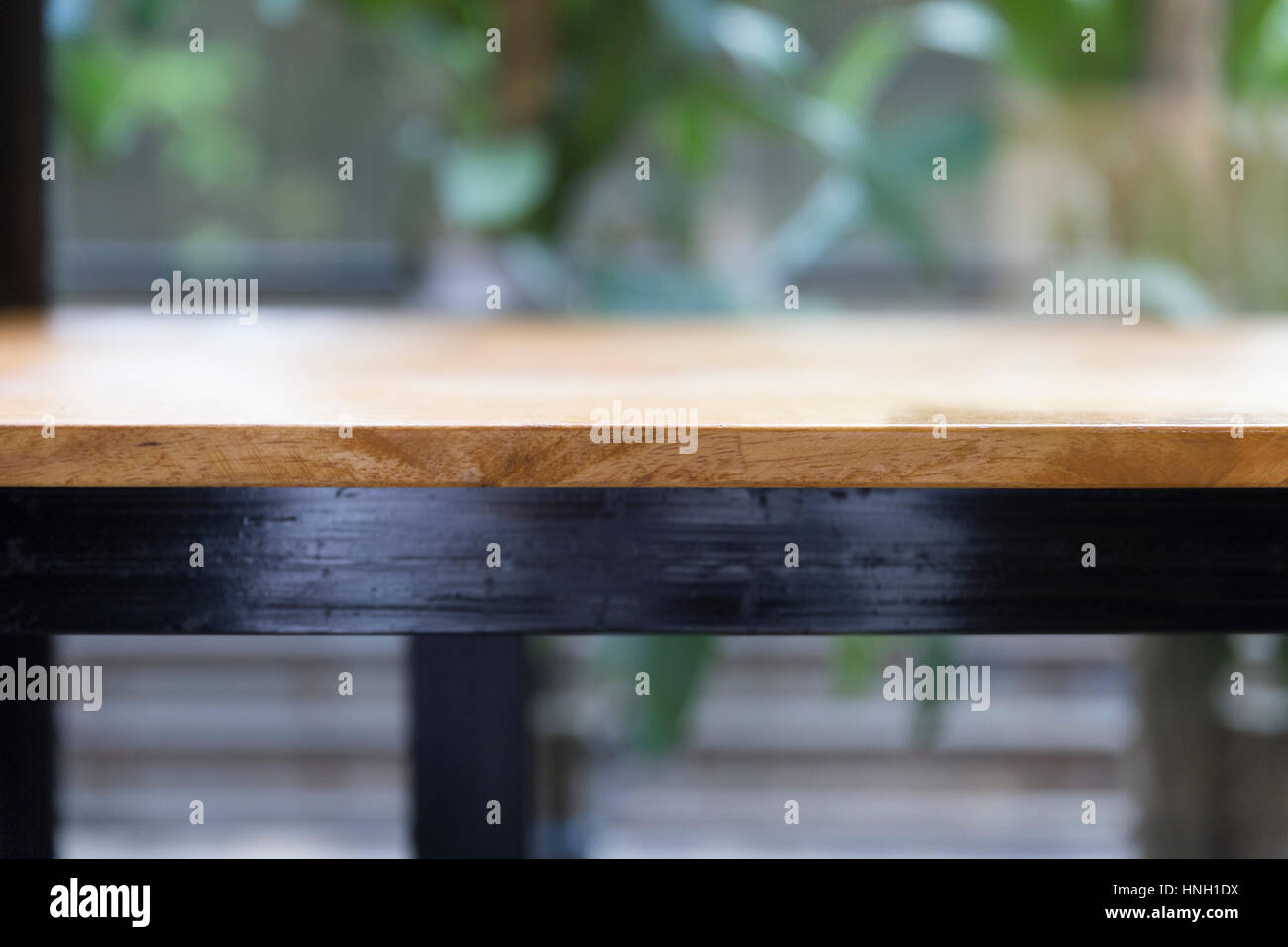wooden table beside window with green leaves background for montage or ...