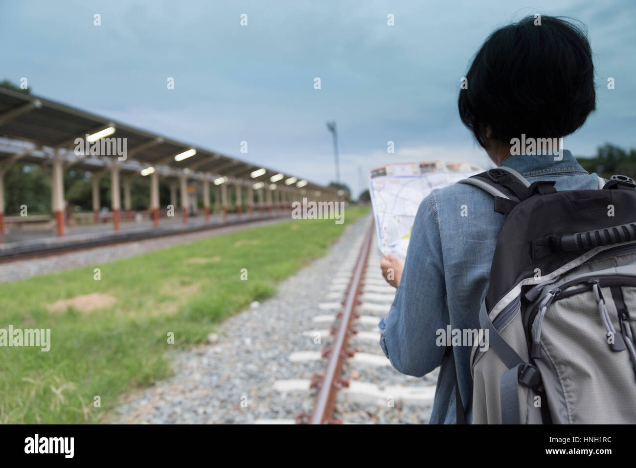 young woman holding map with backpack standing on railway at train ...