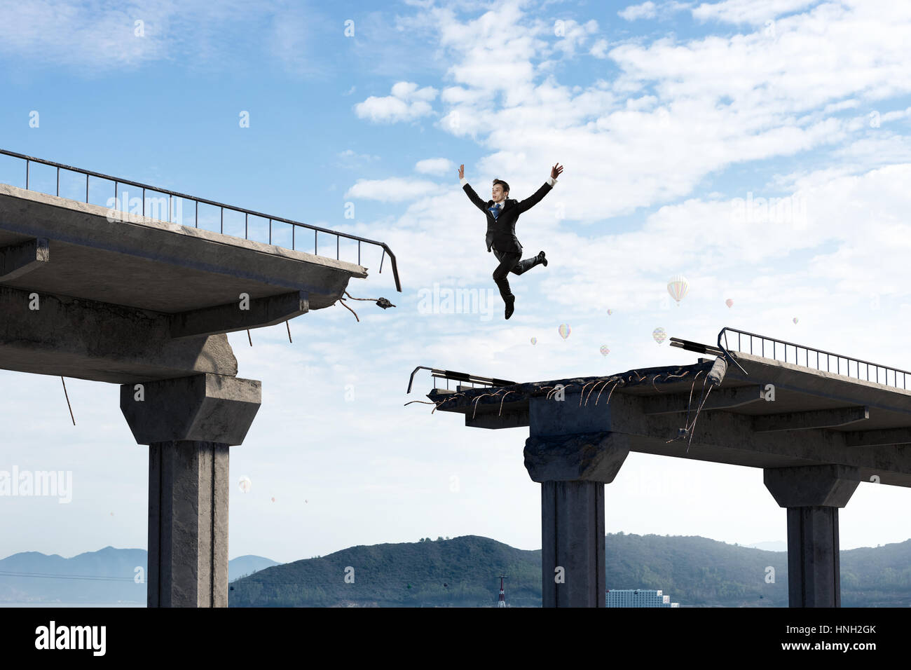 Businessman jumping over a gap in bridge as symbol of problem ...