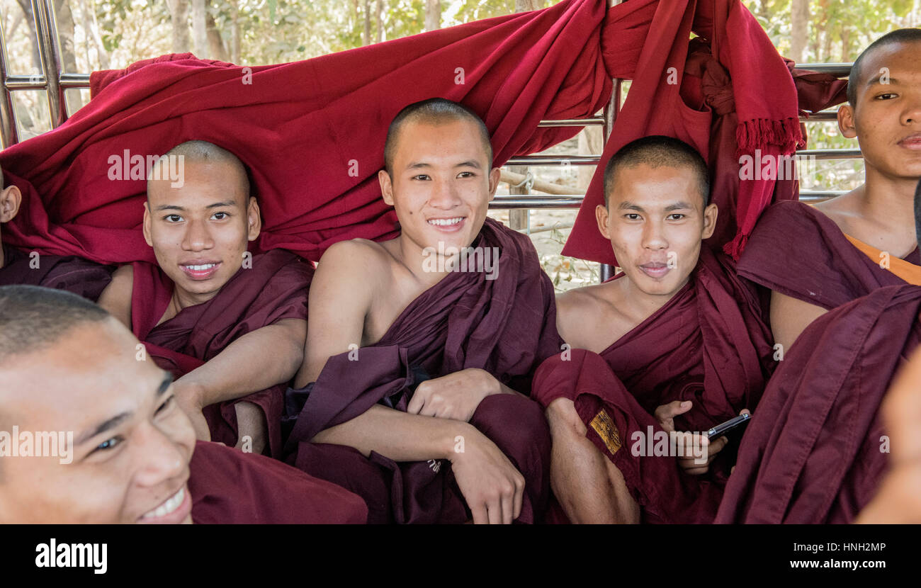 Buddhist monks in crimson robes in back of a van laughing and smiling ...
