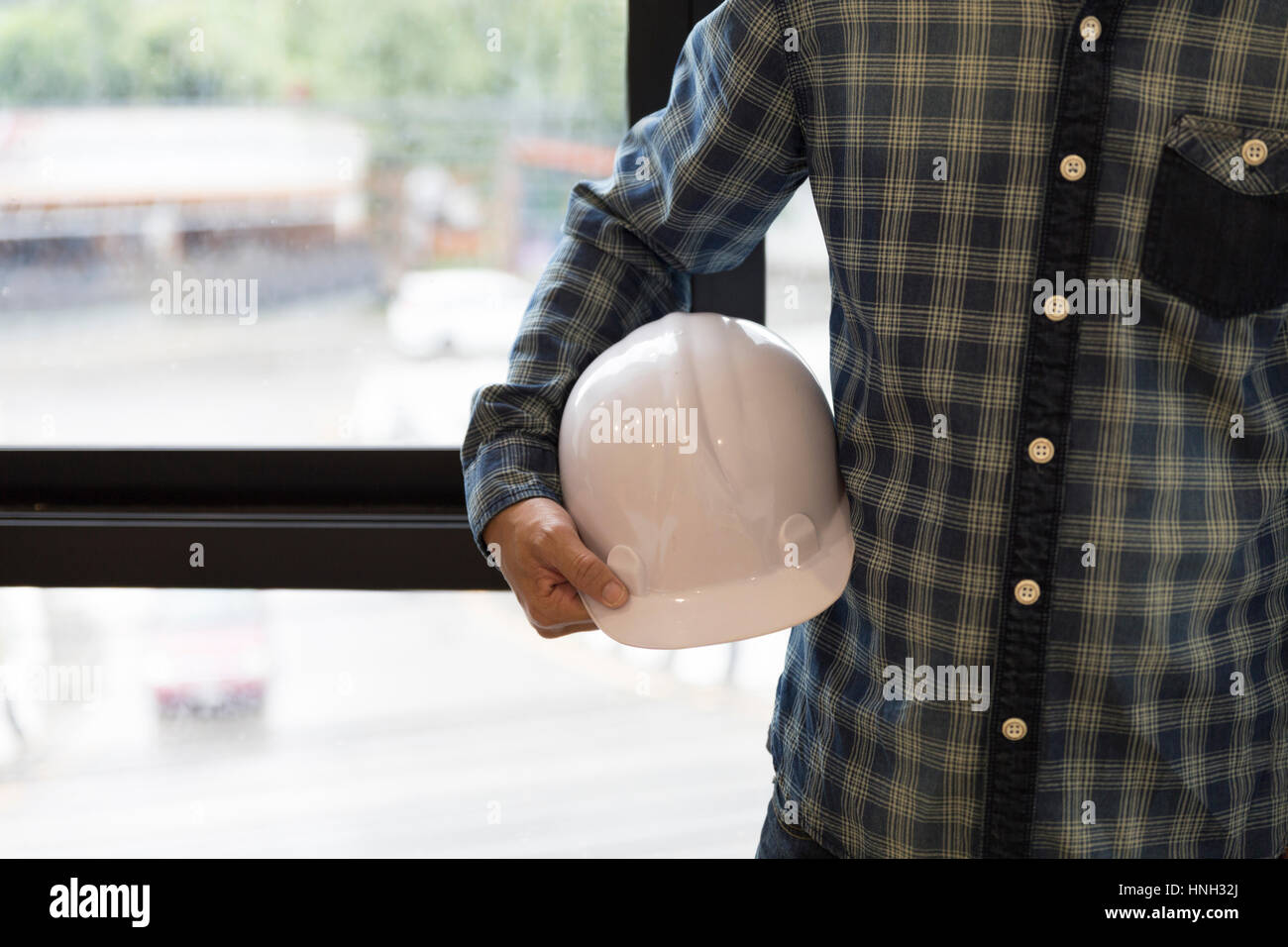 architect engineer holding helmet standing beside window - construction ...