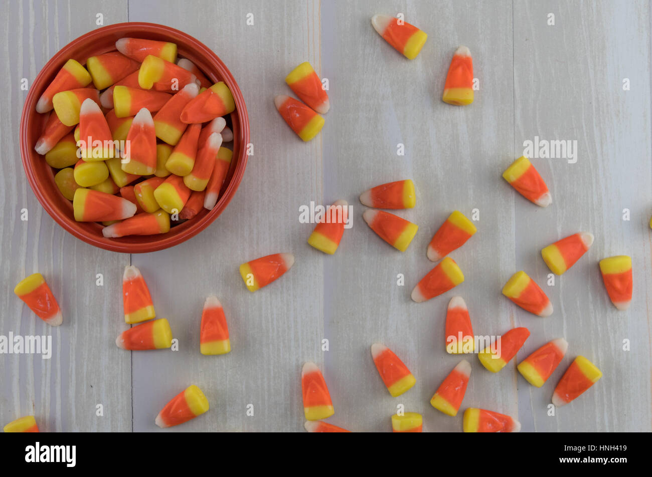 Candy Corn in Orange Bowl with Mess Spill Over across gray background ...