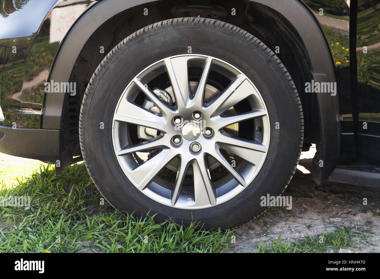 Modern unidentifiable black suv car wheel on rural roadside, closeup ...
