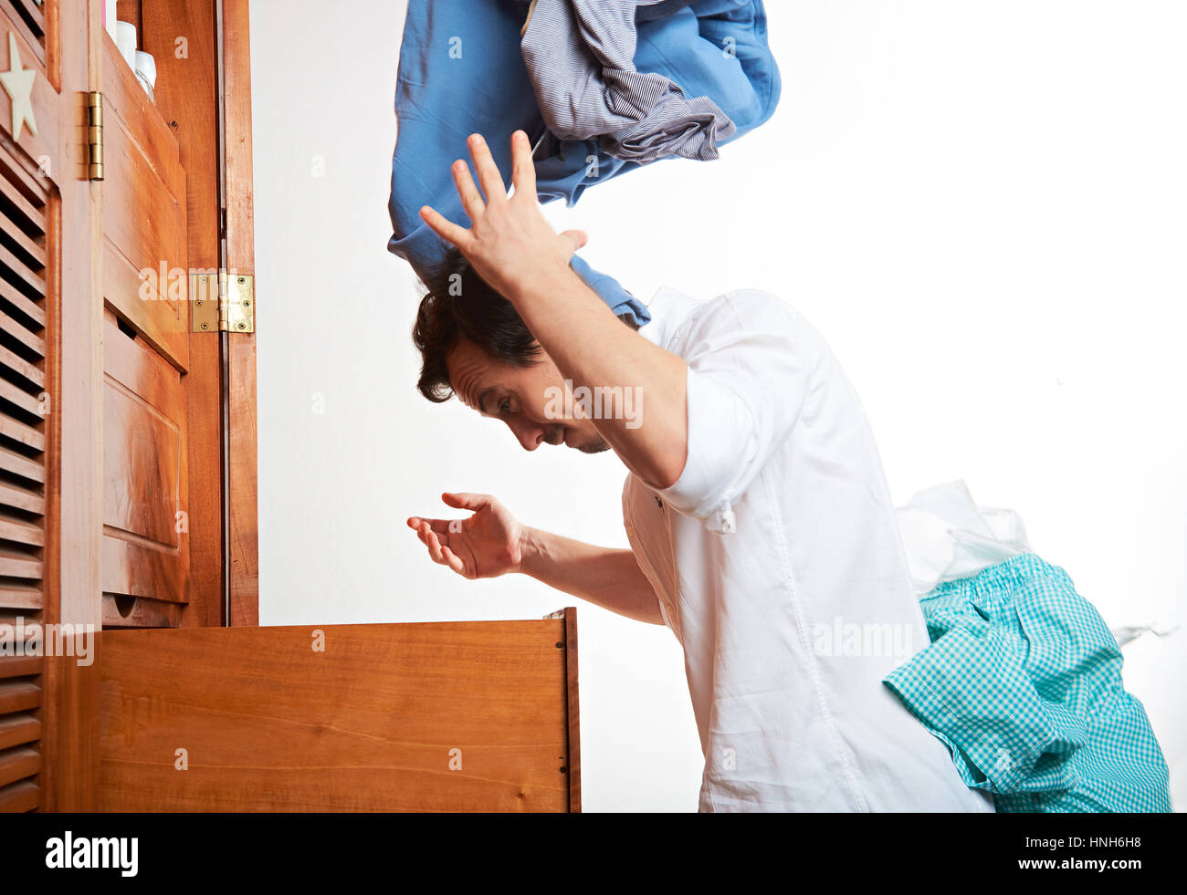 Messy man with clothes in wardrobe. One young man throwing dress from ...