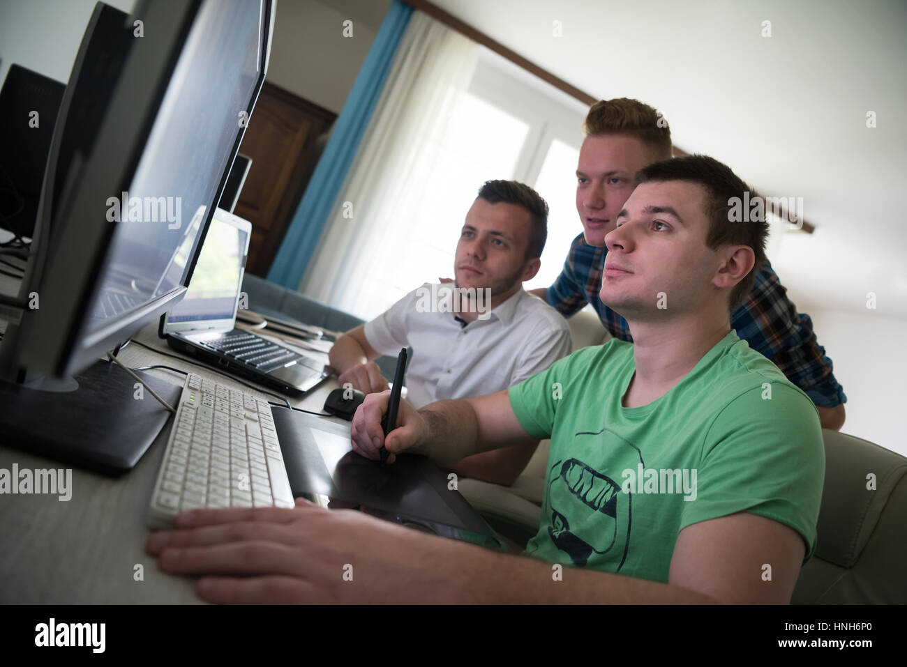 a group of young graphic designers working on a digital tablet and a ...