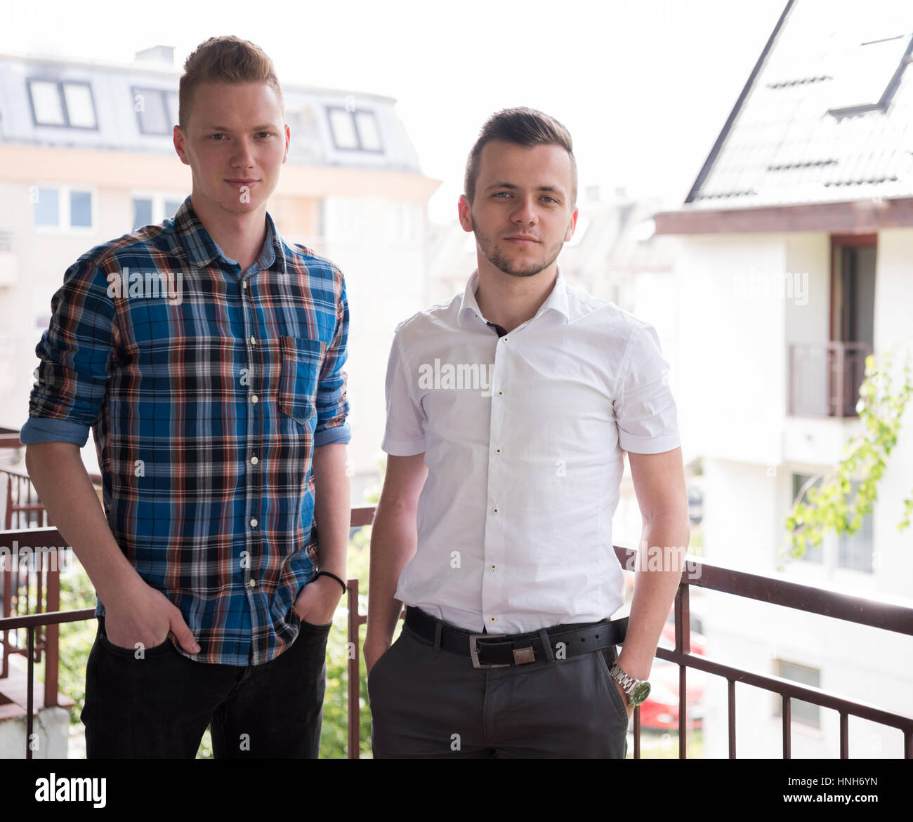 portrait of two young elegant fashion man standing at balcony and ...