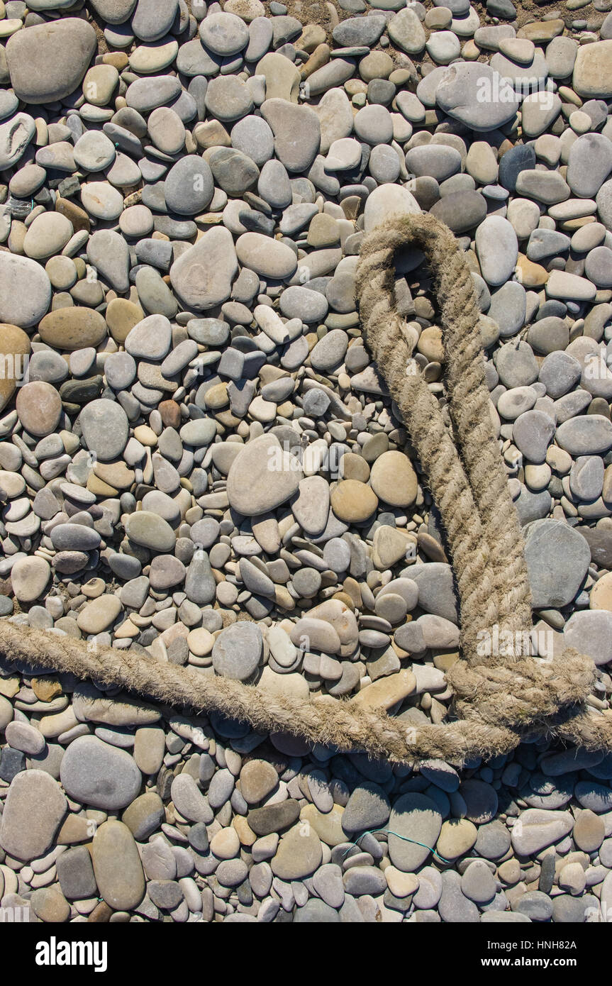 old worn battered marine rope on the pebble beach on a Sunny summer day ...