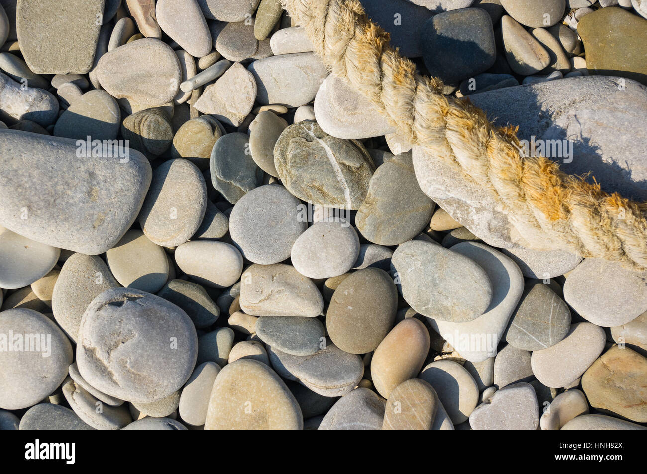 old worn battered marine rope on the pebble beach on a Sunny summer day ...