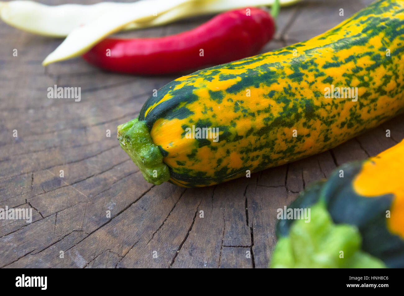unusual green-orange zucchini, pods of white beans and red chilly on an ...