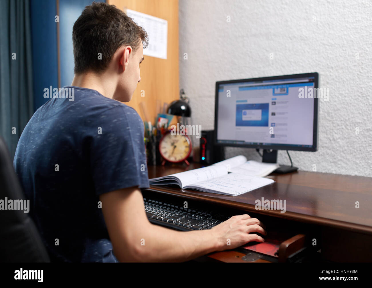 Teenage boy doing homework with the help of computer Stock Photo - Alamy