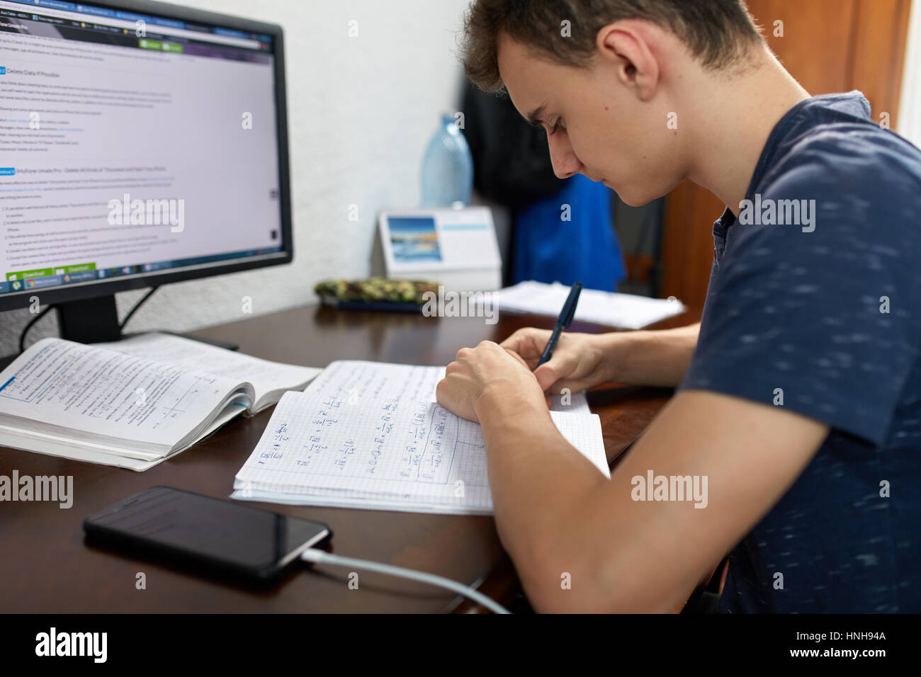 Teenage boy doing homework with the help of computer Stock Photo - Alamy