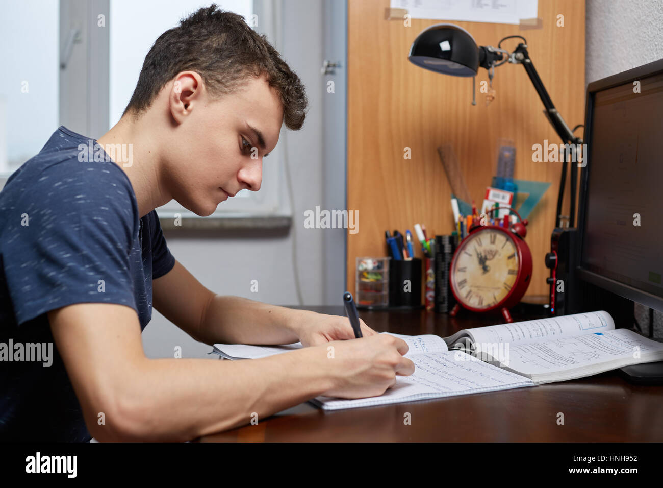 Teenage boy doing homework with the help of computer Stock Photo - Alamy