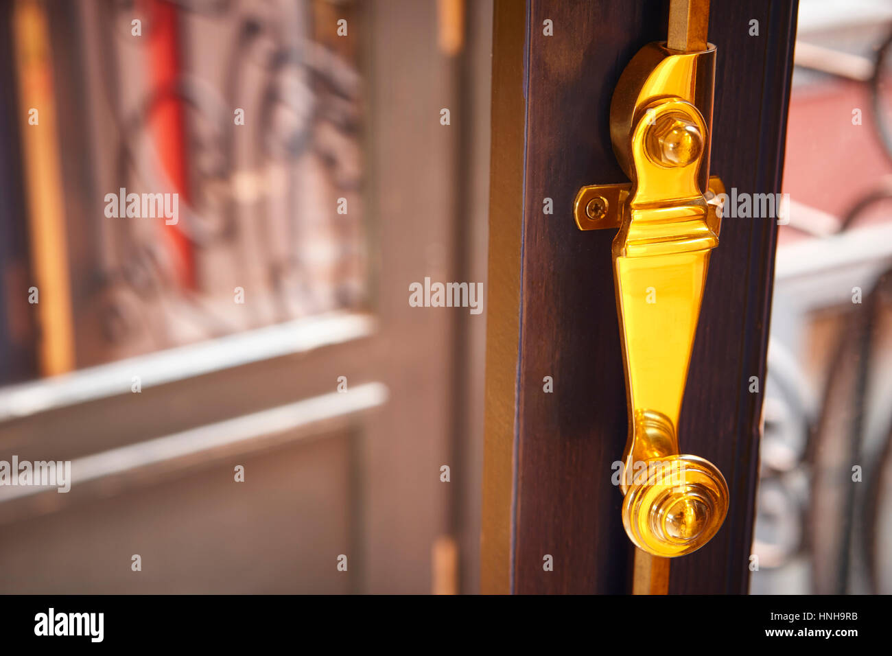 Golden metallic window lock detail with out of focus background ...