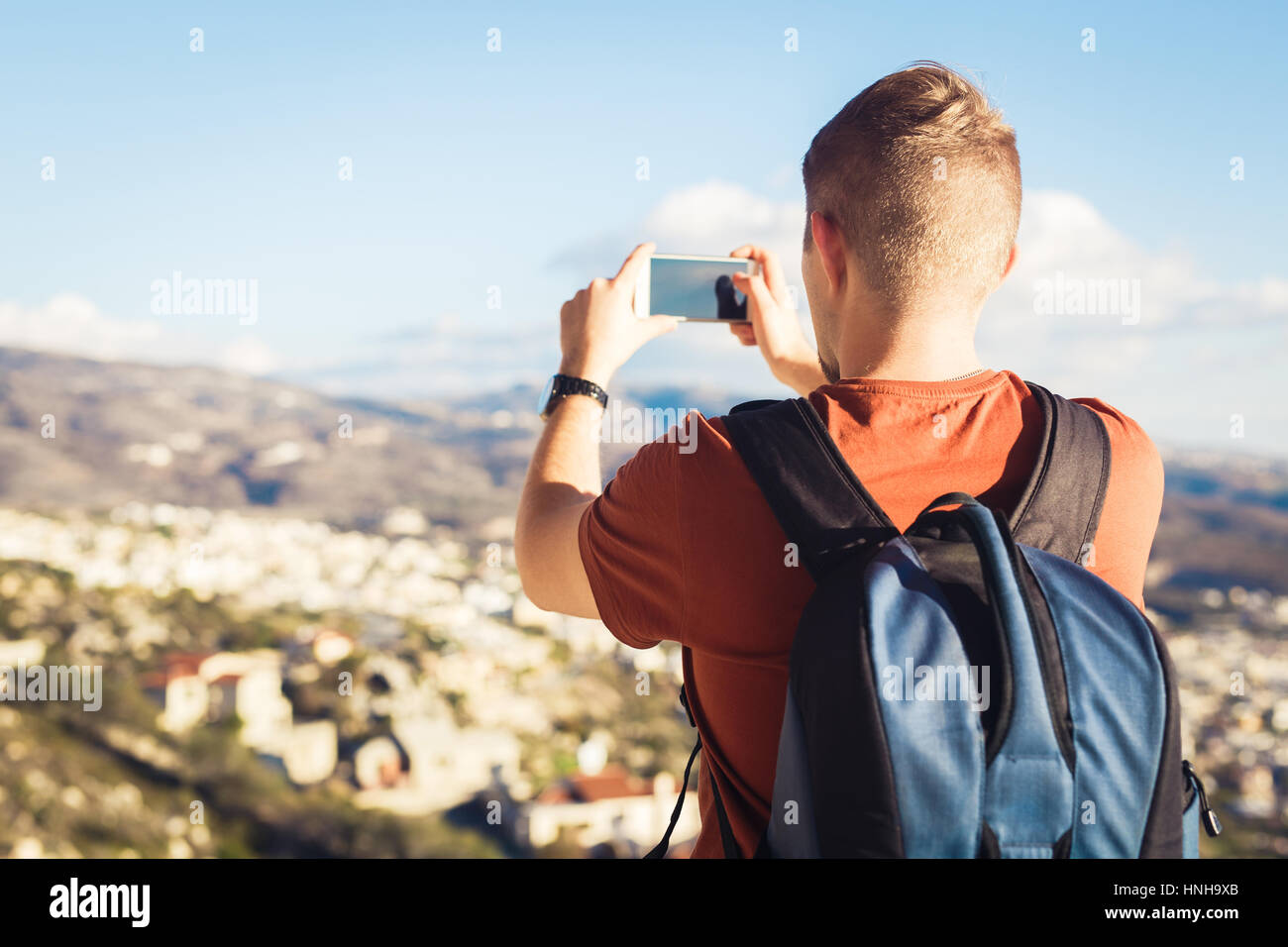 Back view of a young man tourist with backpack taking photo of ...