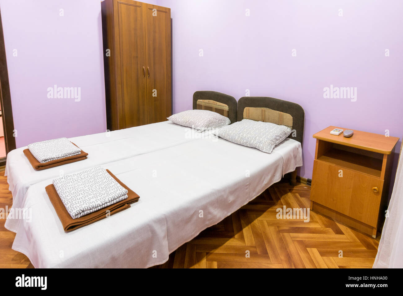 The interior of a small room with a double bed, a bedside table and ...