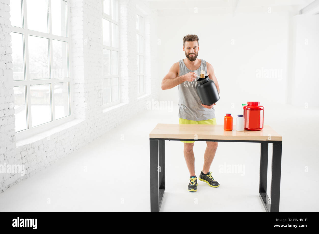 Athletic man in sportswear pouring with scooper protein powder in the ...