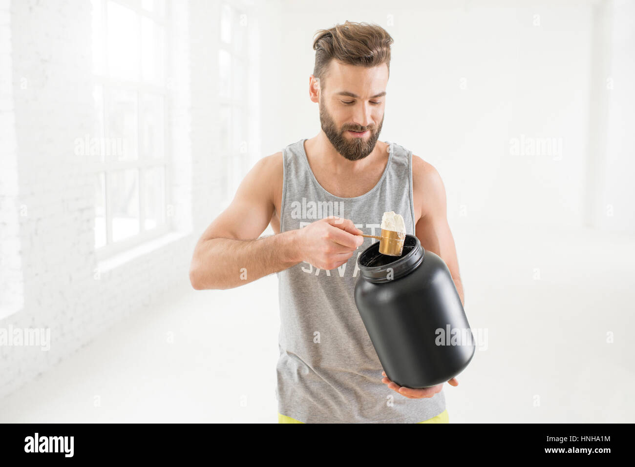 Athletic man in sportswear pouring with scooper protein powder in the ...