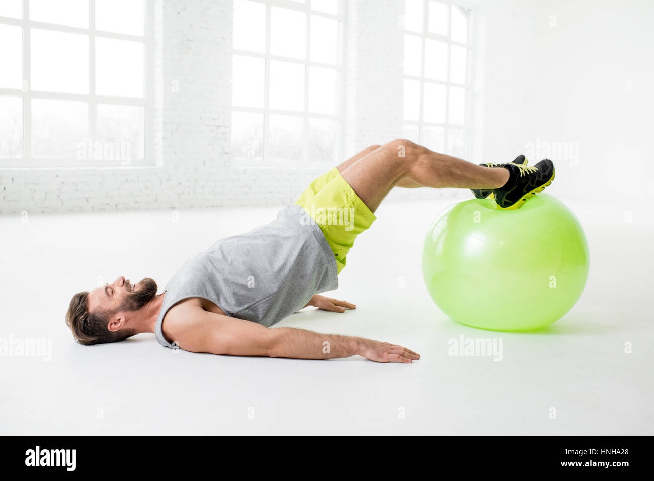 Handsome man exercising with fitball in the white gym interior Stock ...