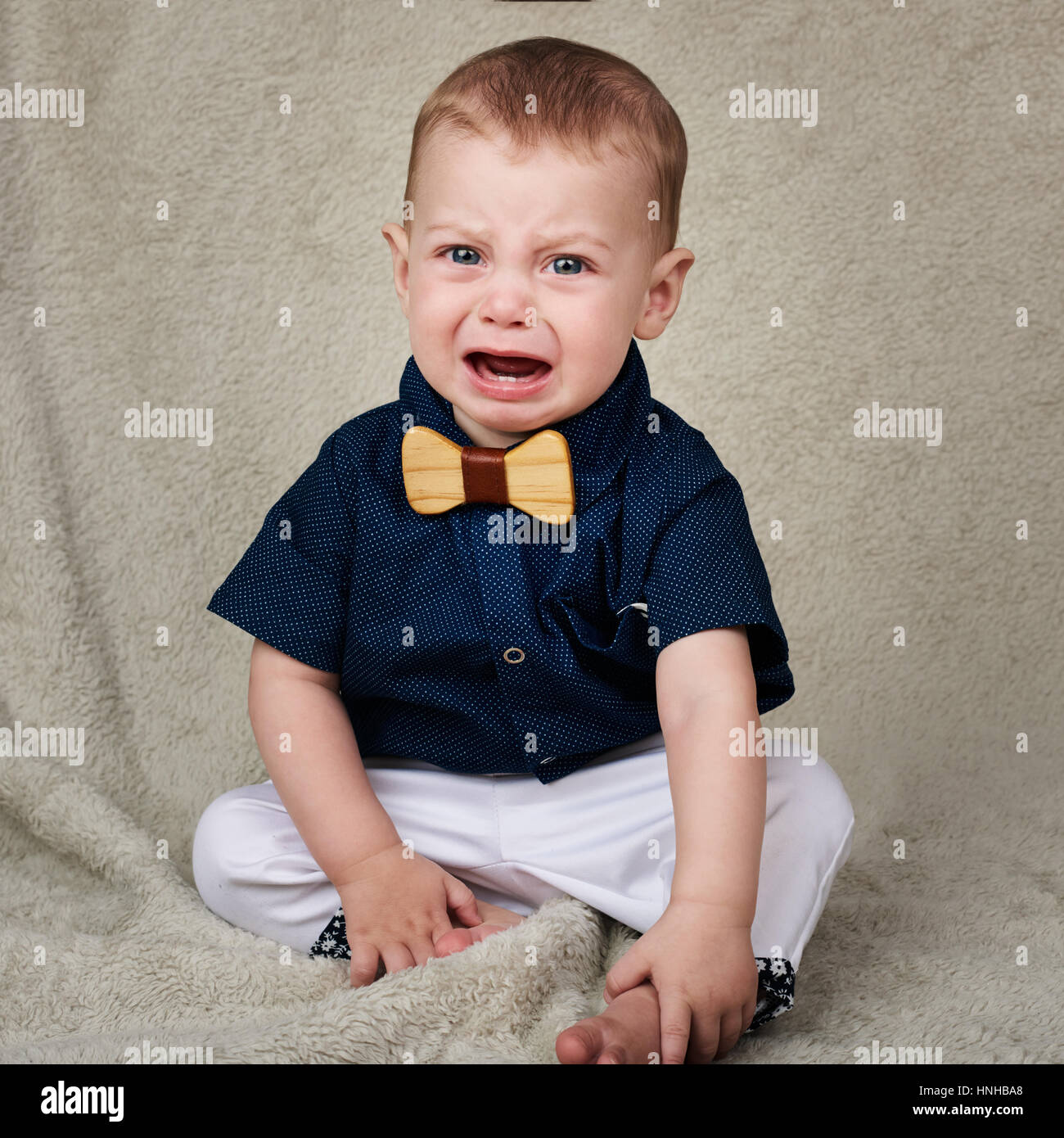 Baby boy crying while looking at camera sitting on blanket Stock Photo ...