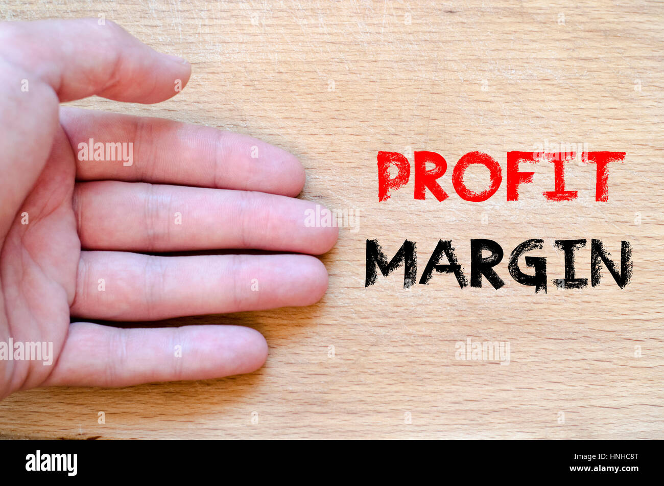 Human hand over wooden background and profit margin text concept Stock ...