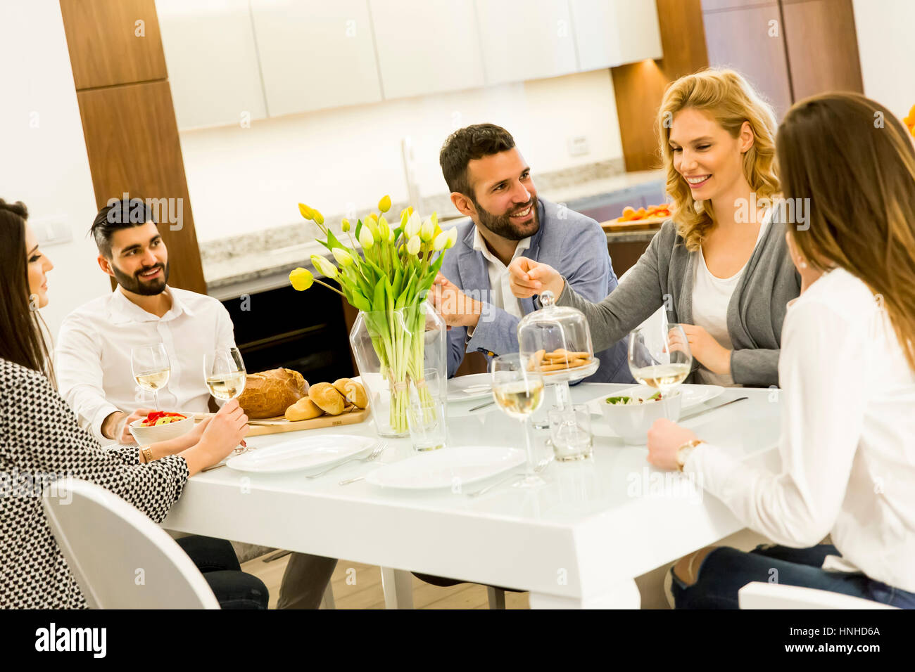 Group of young friends having dinner at home and toasting with white ...