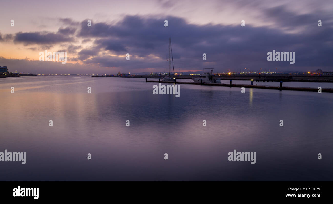 boats in bay at dusk with sun setting over bay and lights in distant ...