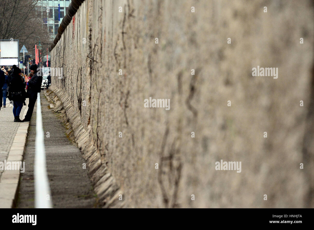 Pedestrian walk by the remnants of the Berlin wall at the memorial site ...