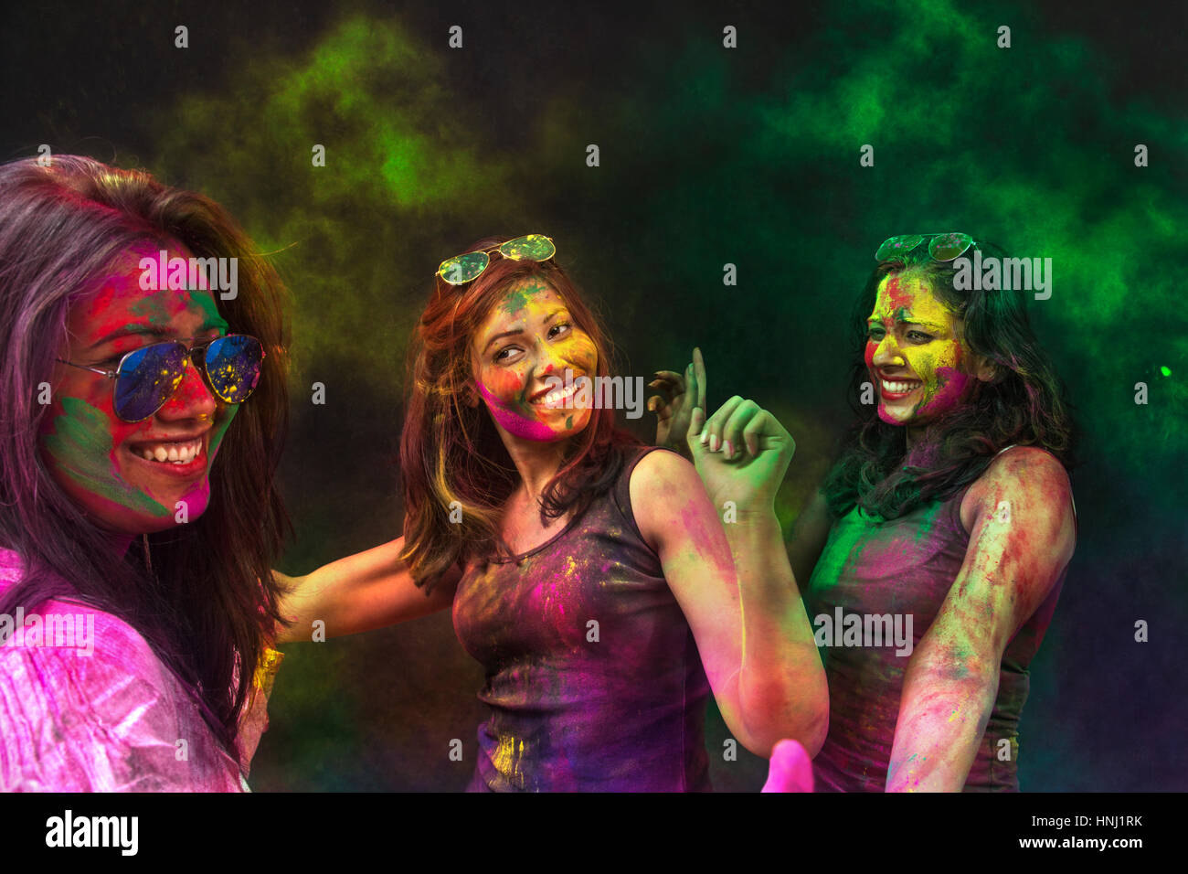 Three Young Indian Women With Colored Face Dancing During Holi Color ...