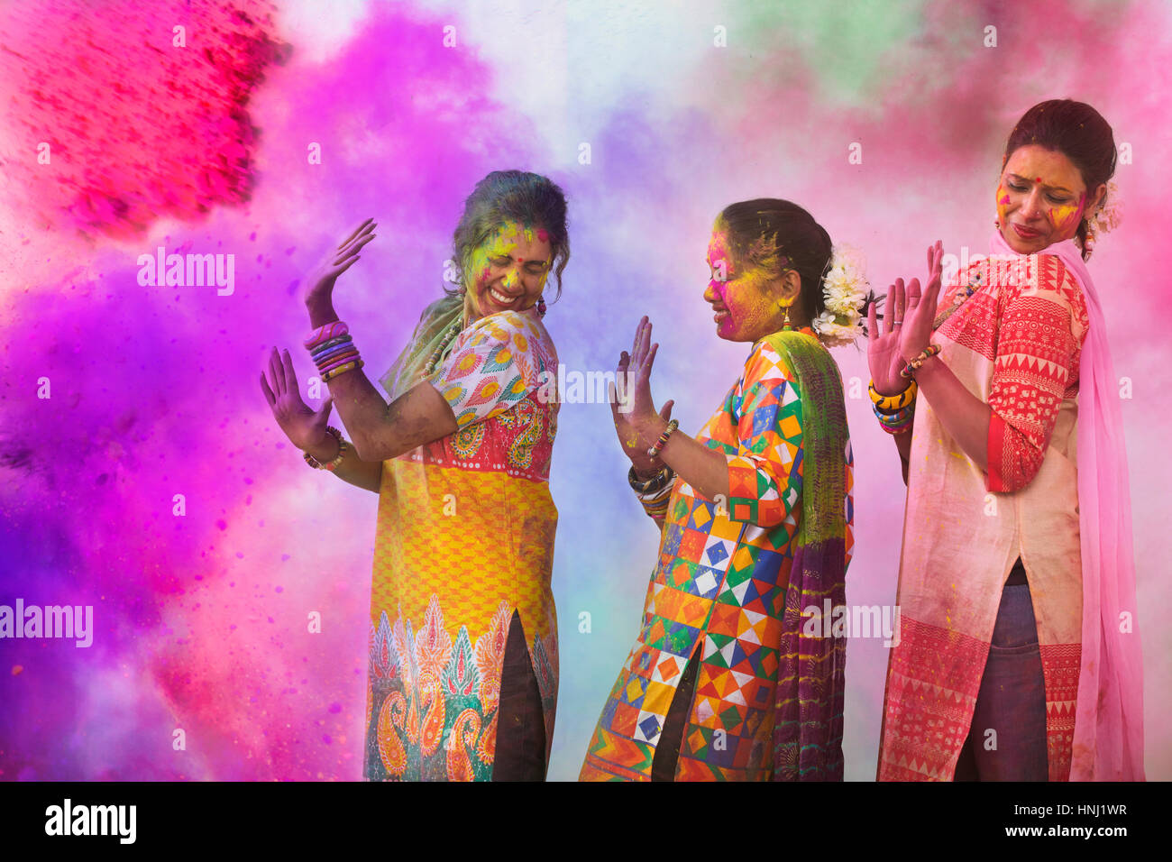 Three Young Indian Women With Colored Face Dancing During Holi Color ...