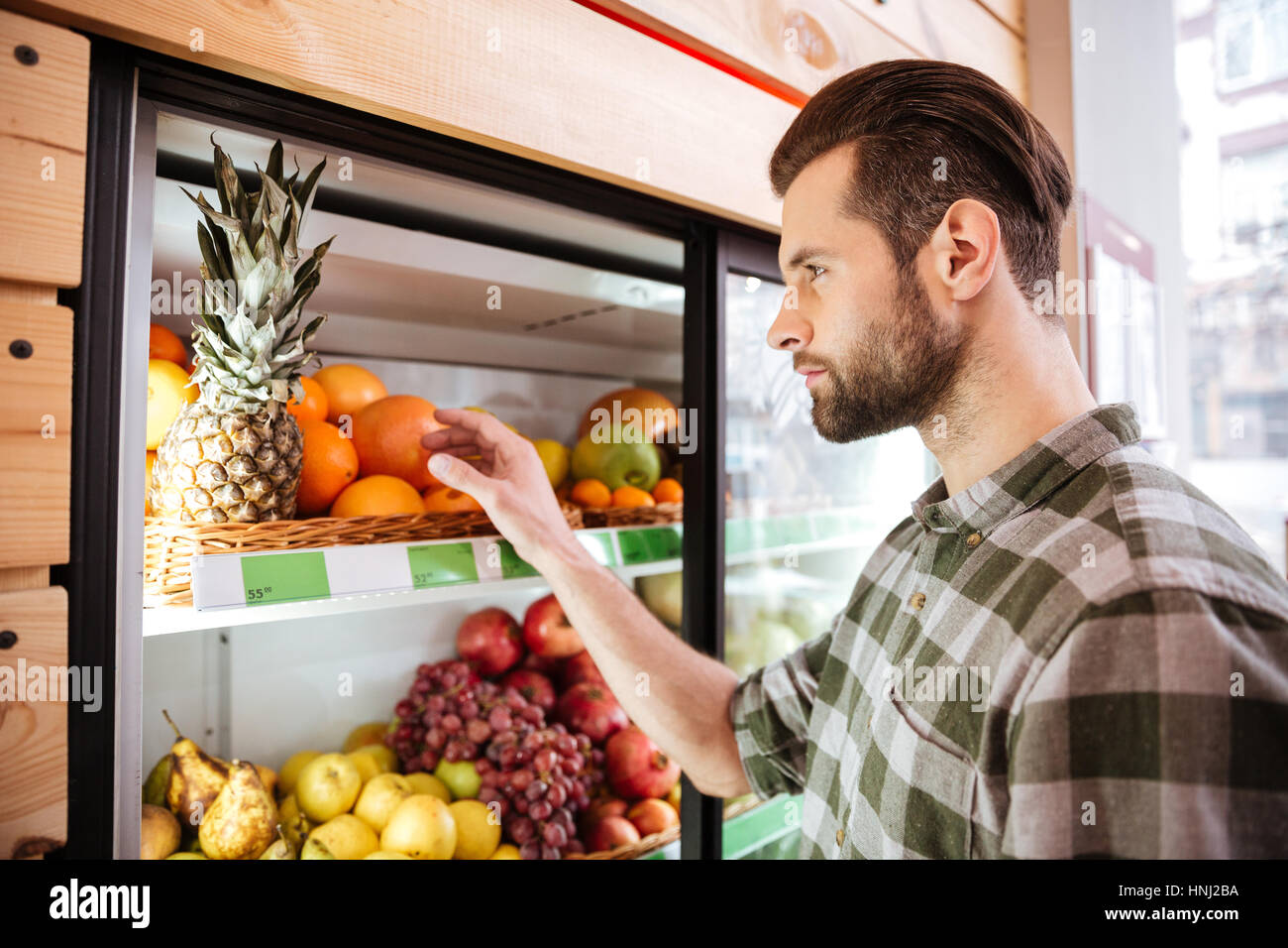 Attractive young man buying fresh fruits in grocery shop Stock Photo ...
