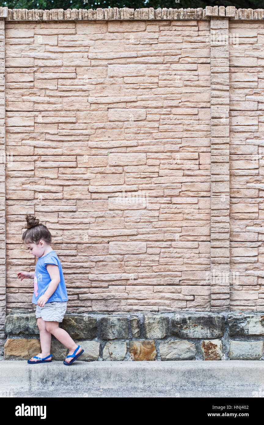 Side view of girl walking on footpath against wall Stock Photo - Alamy