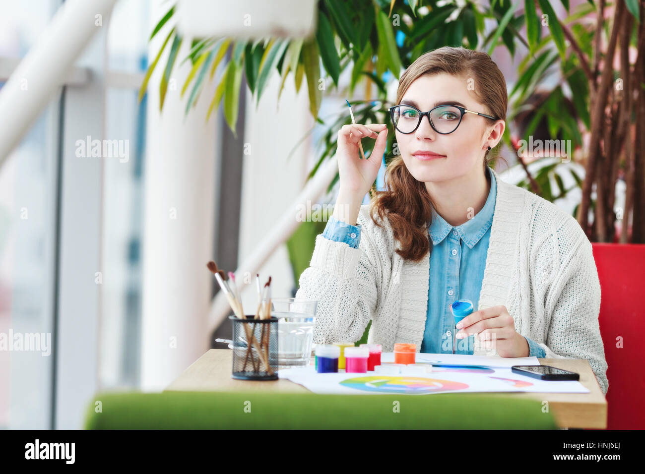 Girl with glasses sitting with colorful paints Stock Photo - Alamy