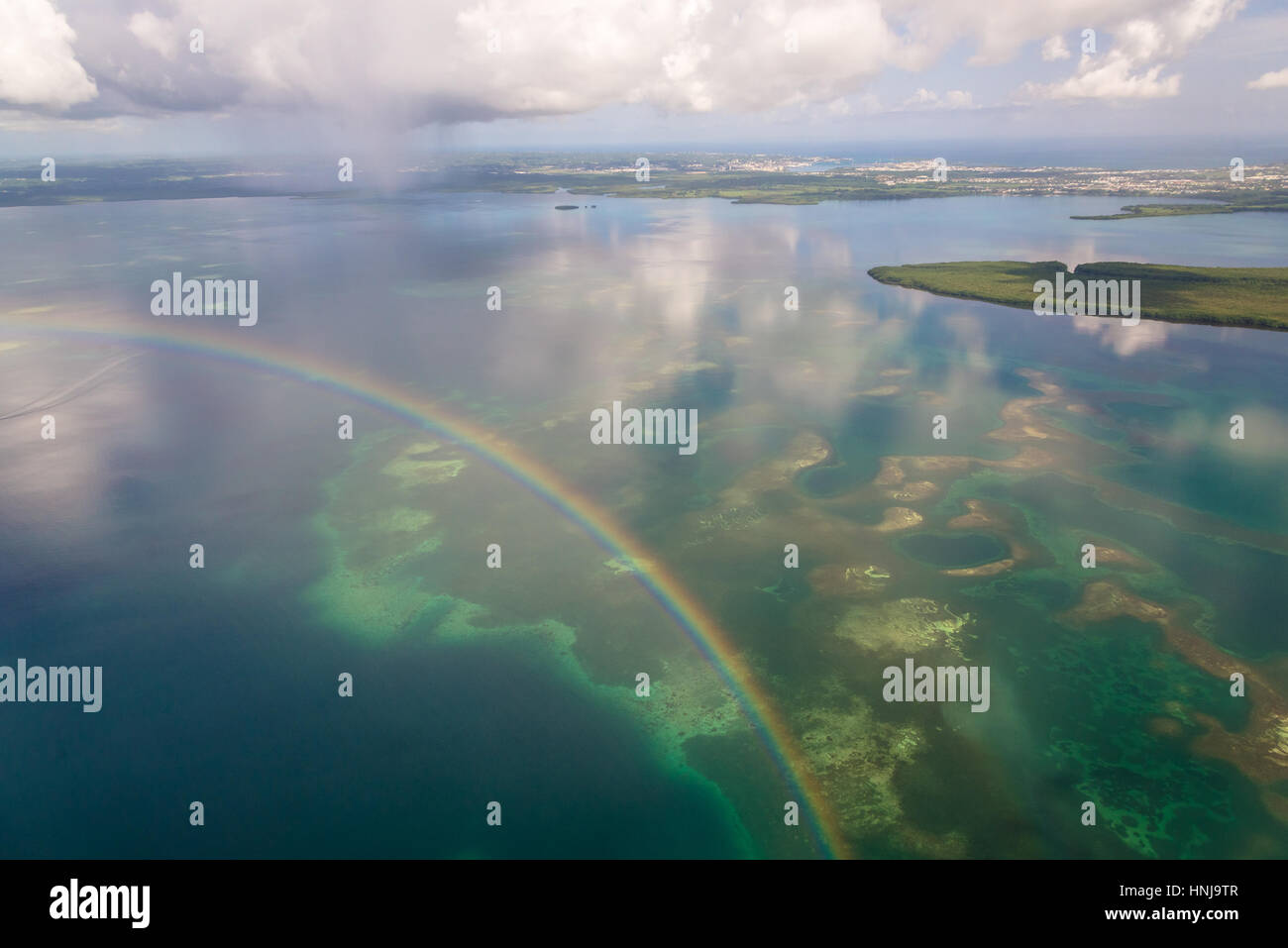 Aerial approach to Guadeloupe with mirrored rainbow and cloudscapes ...