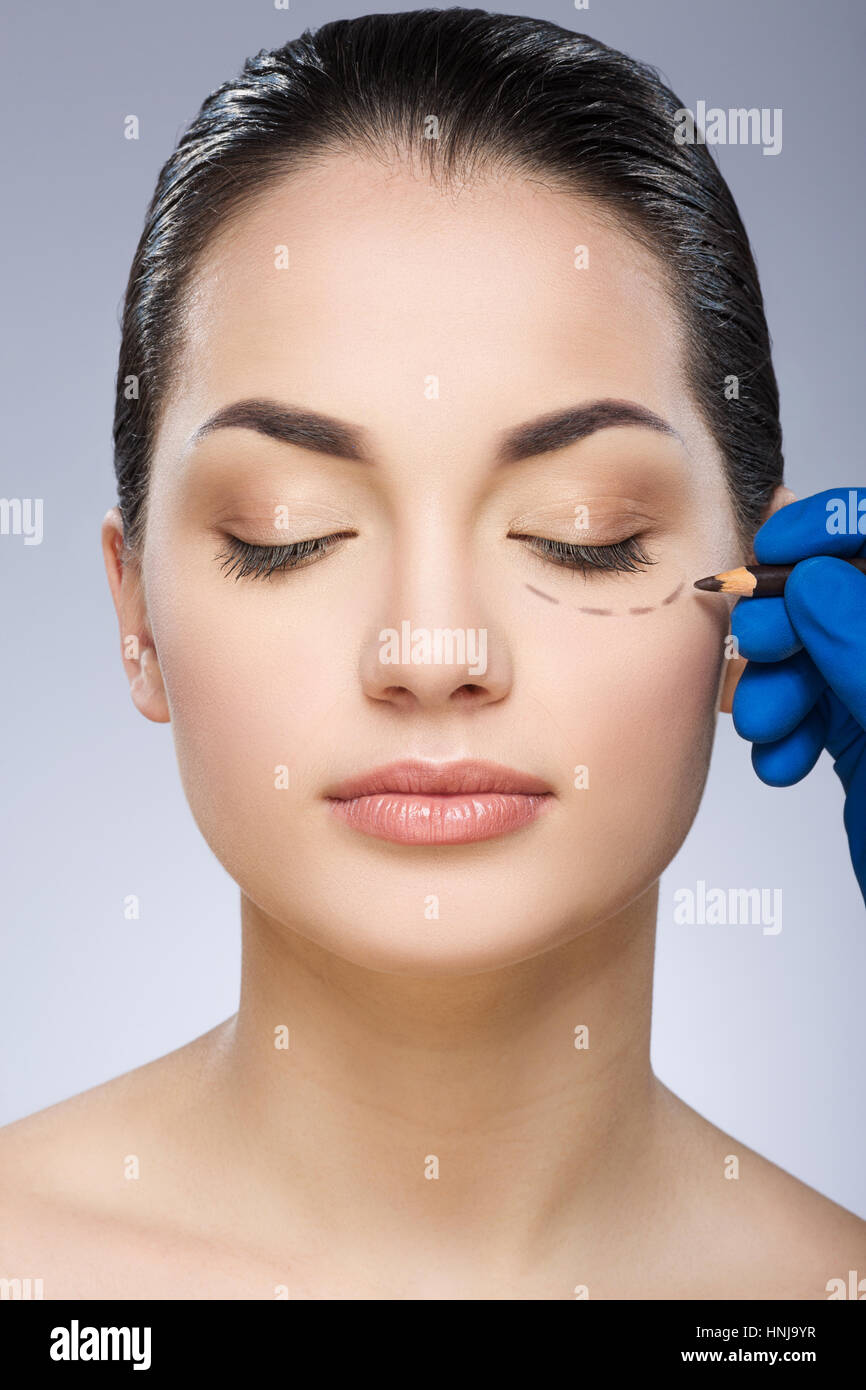 Doctor drawing dashed line under eye Stock Photo - Alamy