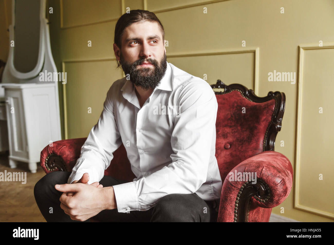 Handsome man sitting on red chair Stock Photo - Alamy