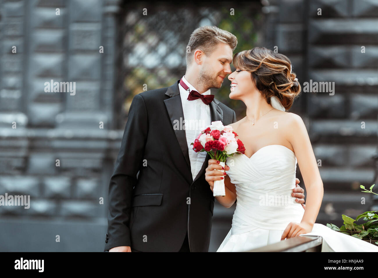 Bride and bridegroom standing with bouquet and smiling Stock Photo - Alamy