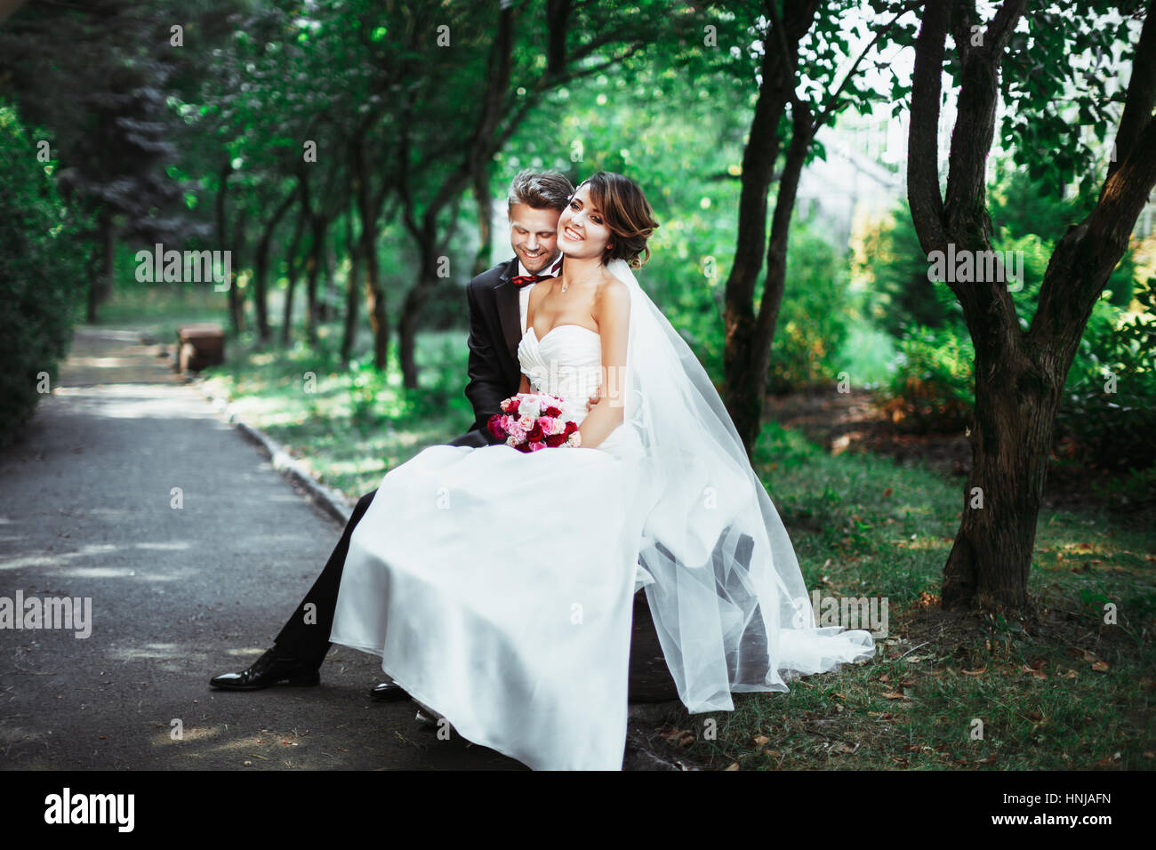 Bride and groom sitting on bench Stock Photo - Alamy