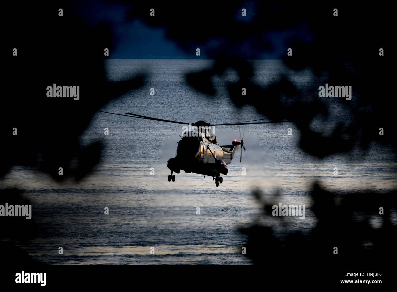 Navy rescue helicopter hovering over water Stock Photo - Alamy