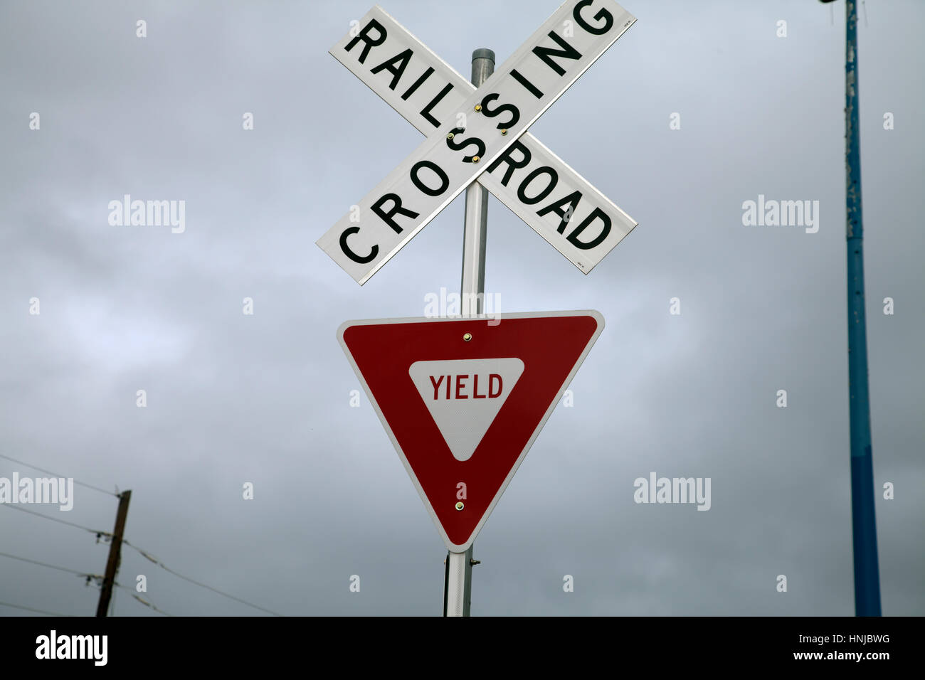 Close up of a railroad crossing and yield sign against a stormy sky ...