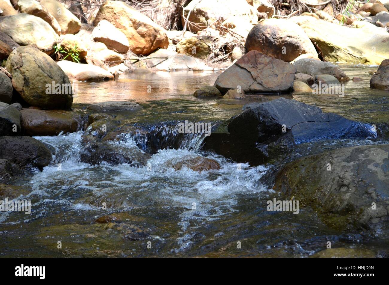 River flowing over rocks creating a tiny waterfall Stock Photo - Alamy