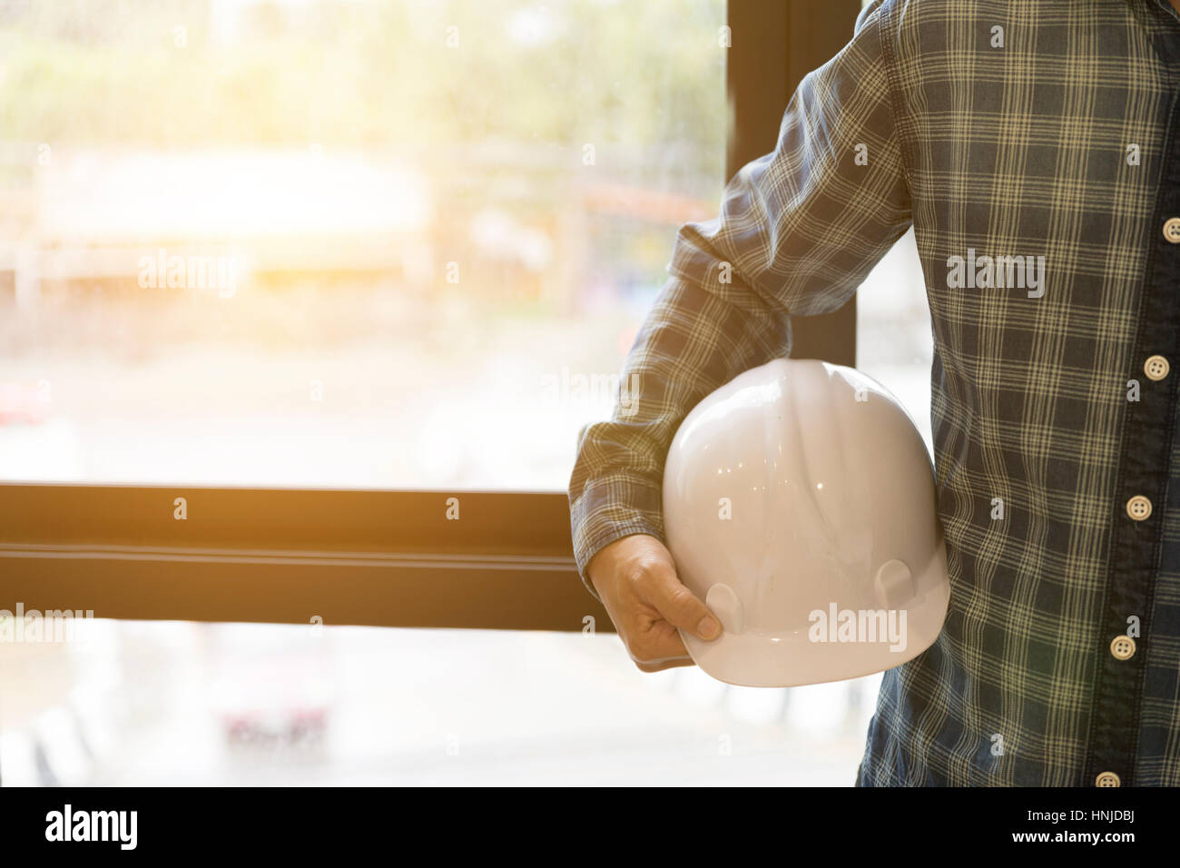 architect engineer holding helmet standing beside window - construction ...