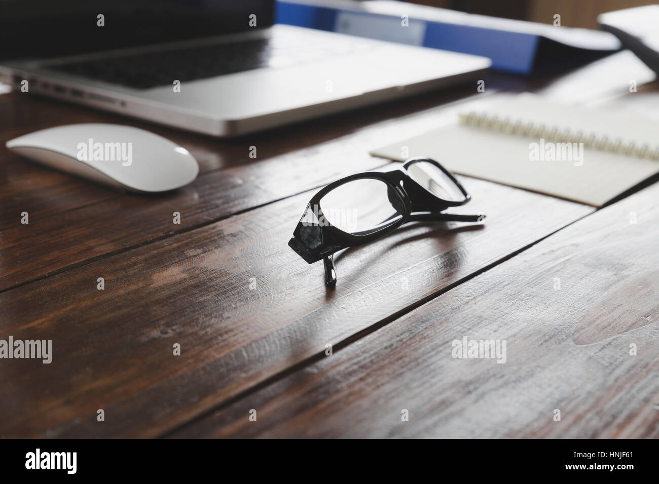 eyeglasses, laptop computer and notepad on wooden office desk Stock ...