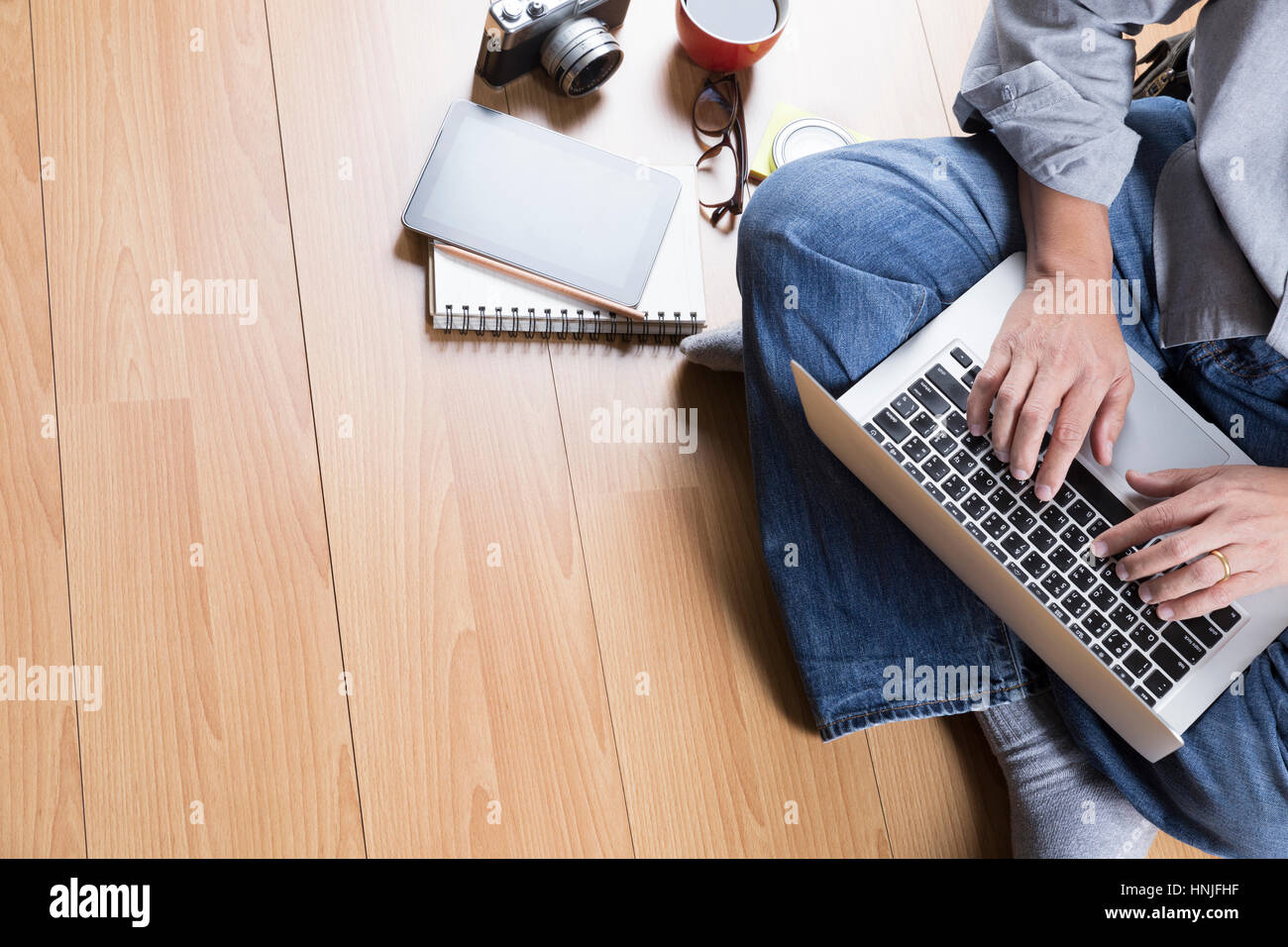 man sitting on floor with laptop computer, coffee cup and tablet - top ...