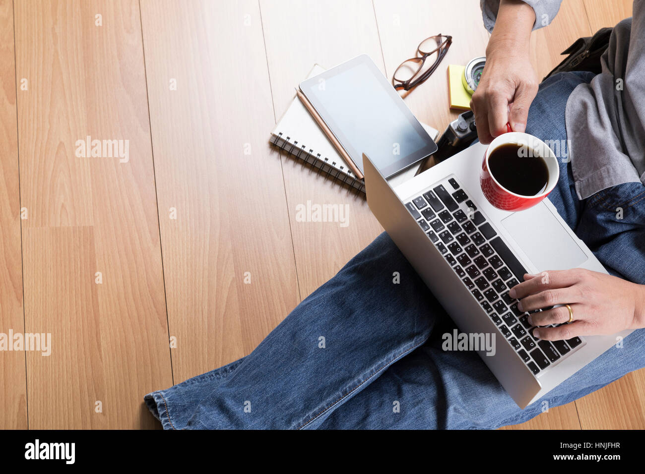 man sitting on floor with laptop computer, coffee cup and tablet - top ...