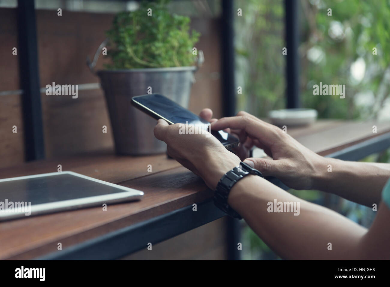 man's hand using smartphone with digital tablet on wooden table ...