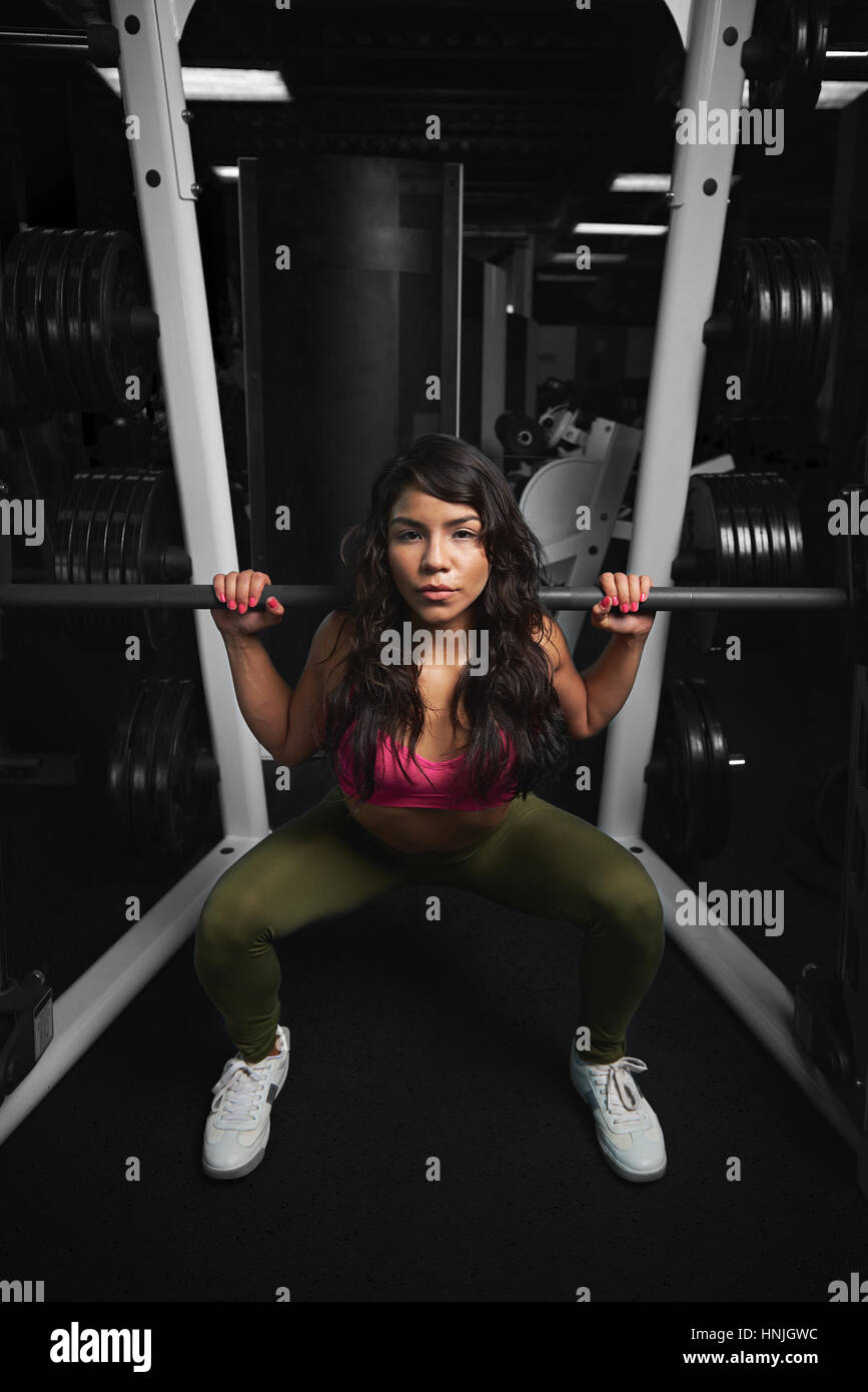 Young woman doing barbell workout in dark black gym background Stock ...